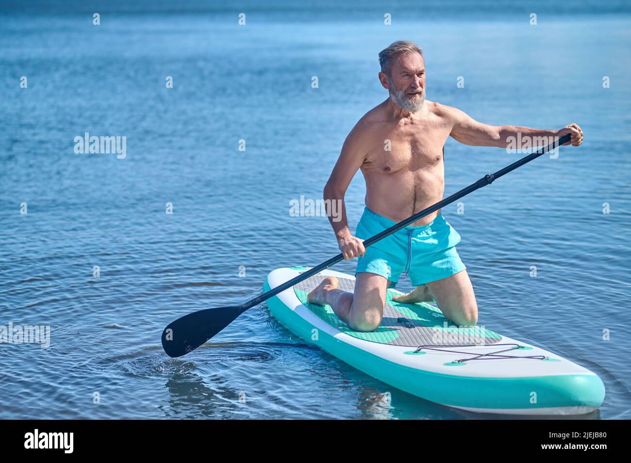 Man with paddle on rowing board on water Stock Photo - Alamy