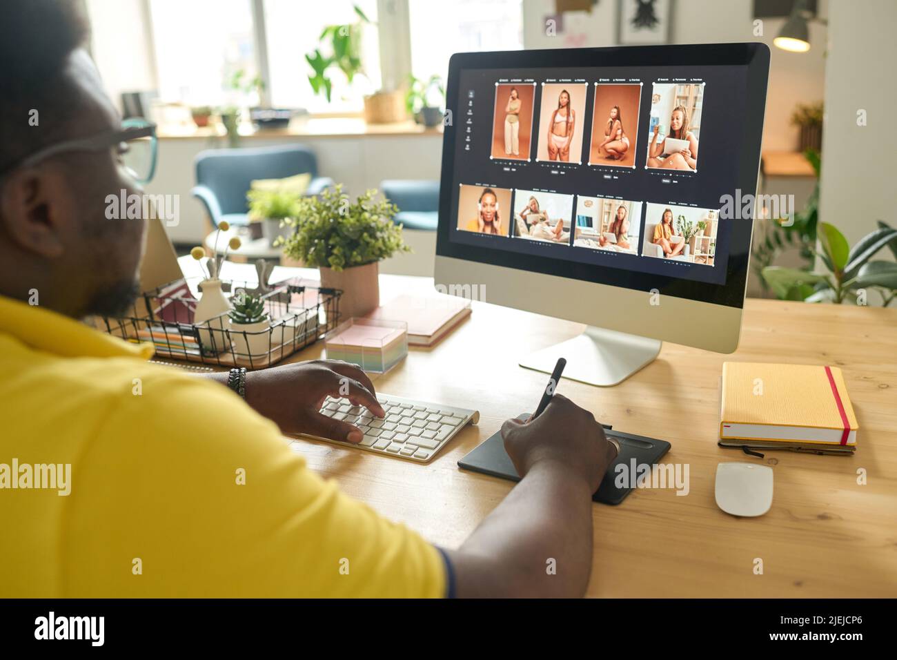 Photo editor working on desktop computer at office desk retouching ...