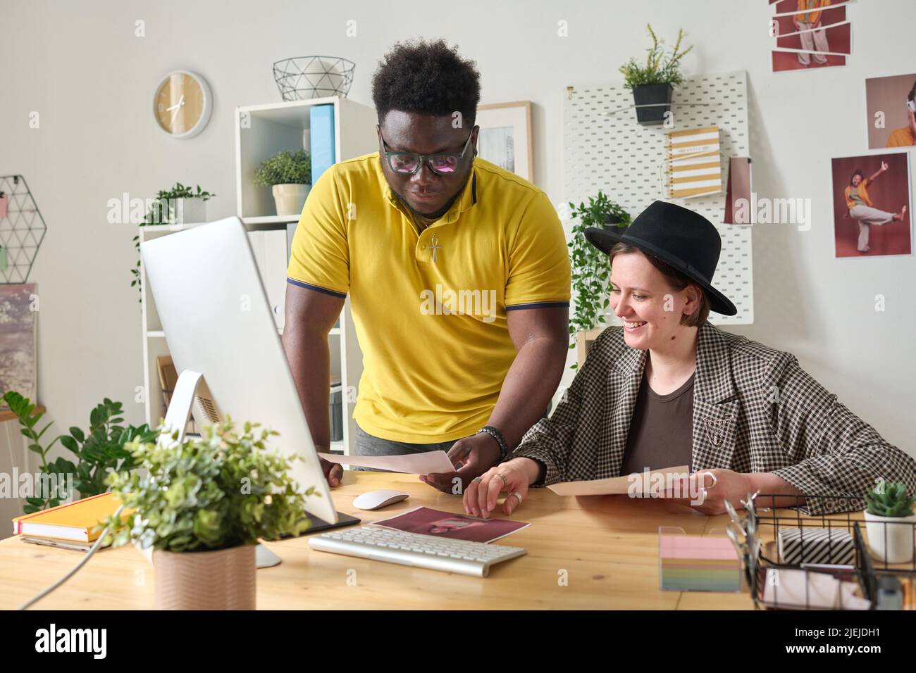 Photo editor discussing professional photos with designer at table with ...
