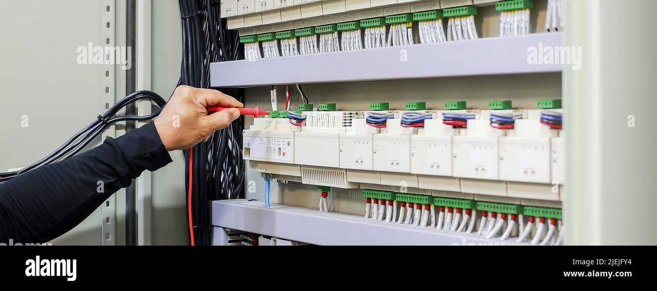 Electrical engineers check electrical control devices with a multimeter ...
