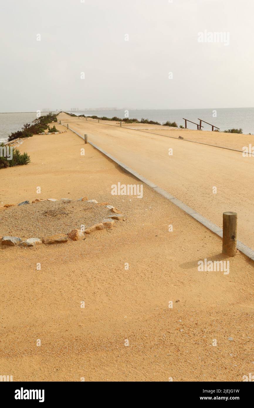 path of dirt road next the water ocean with reflection of sunlight ...
