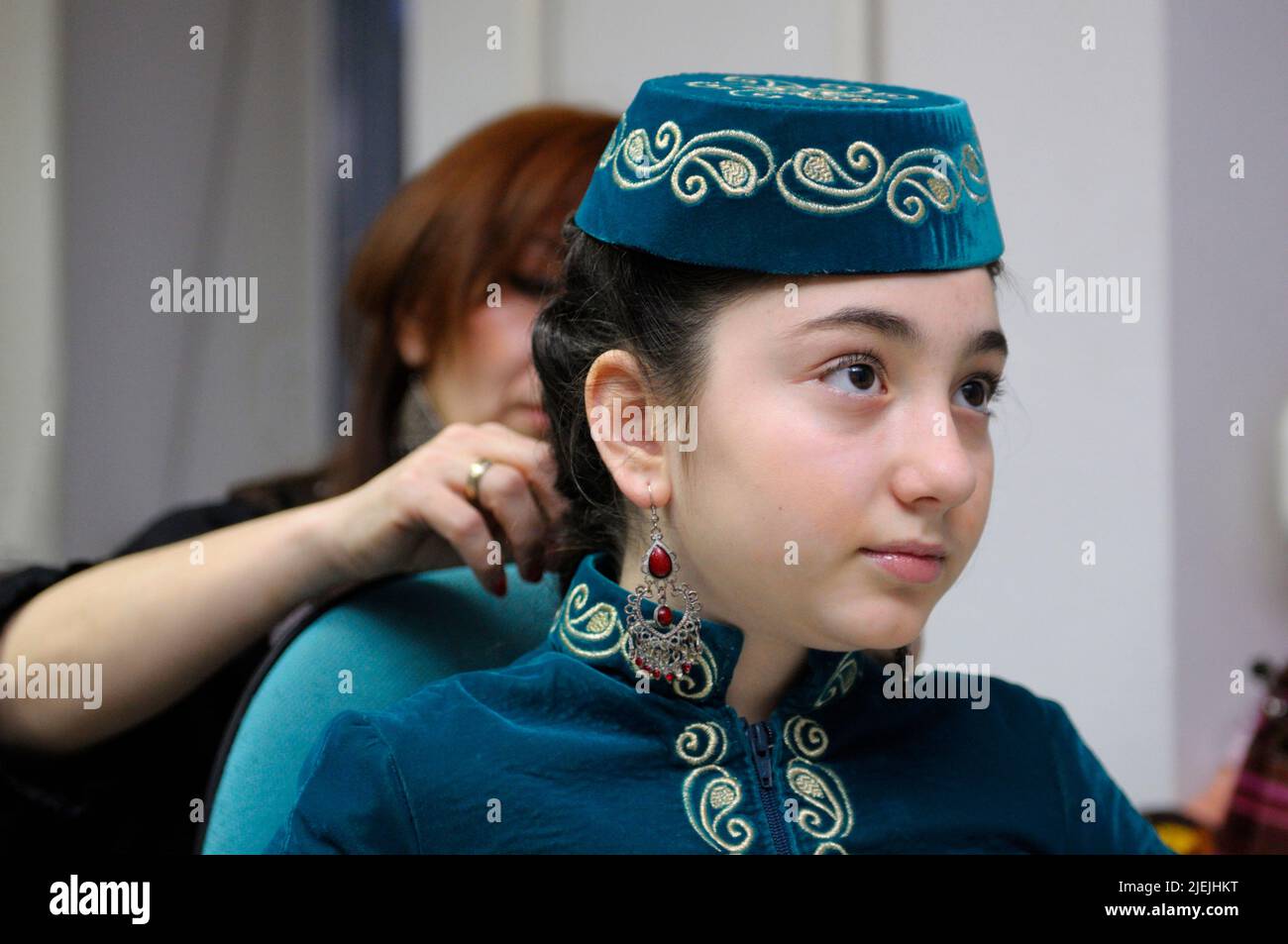 Woman hands making the tight braid of little girl dressed in national ...