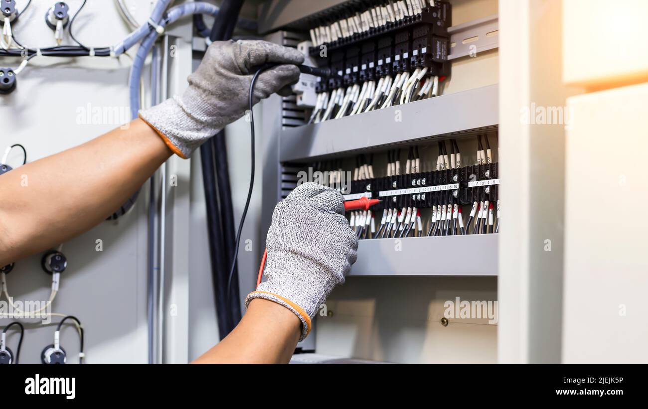 Electrical engineers check electrical control devices with a multimeter ...