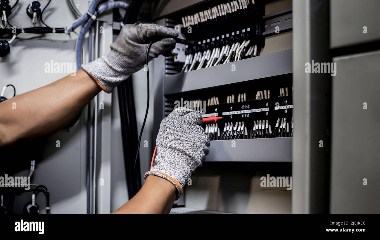 Electrical engineers check electrical control devices with a multimeter ...