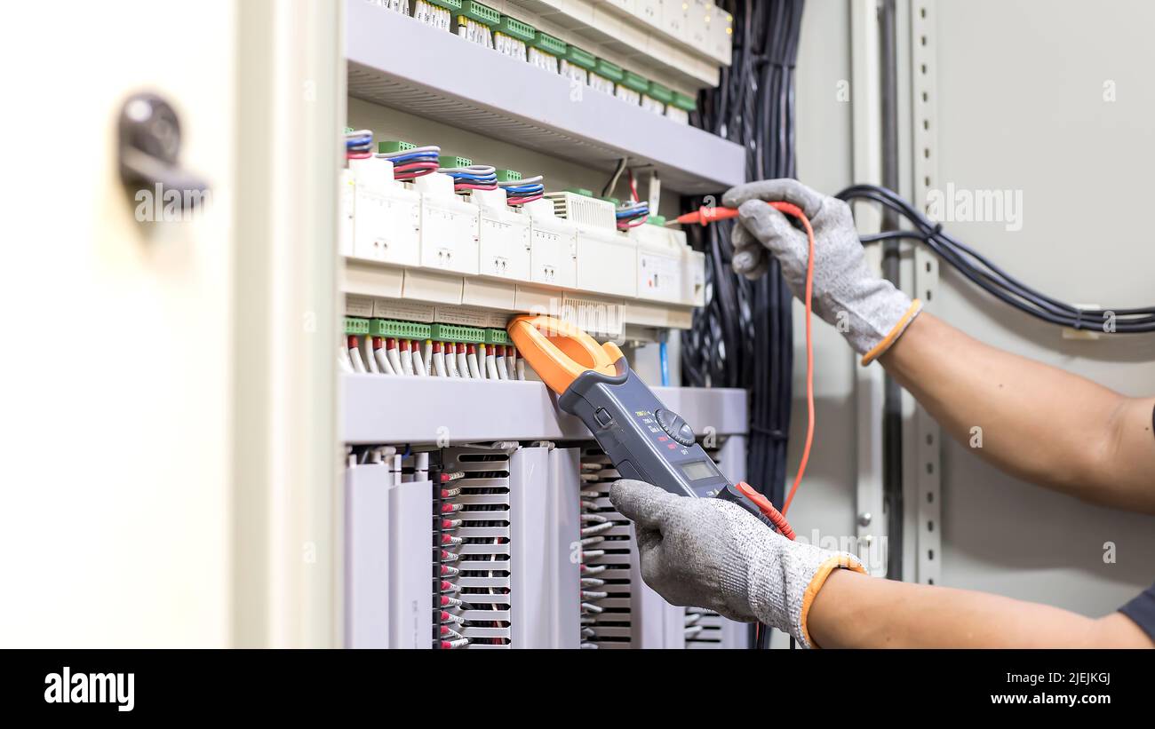 Electrical engineers check electrical control devices with a multimeter ...
