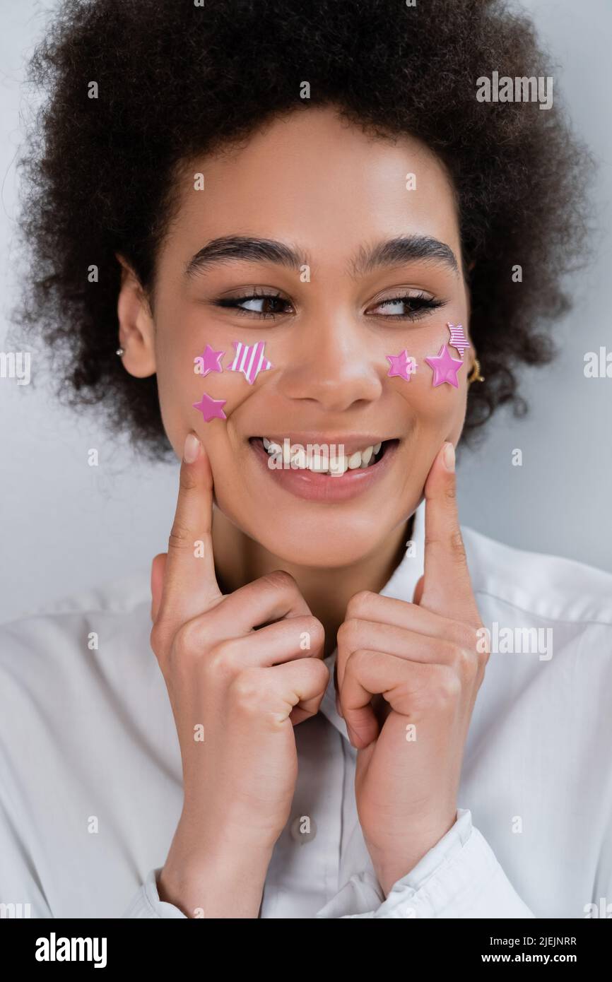 portrait of african american woman pointing with fingers at cheeks with ...
