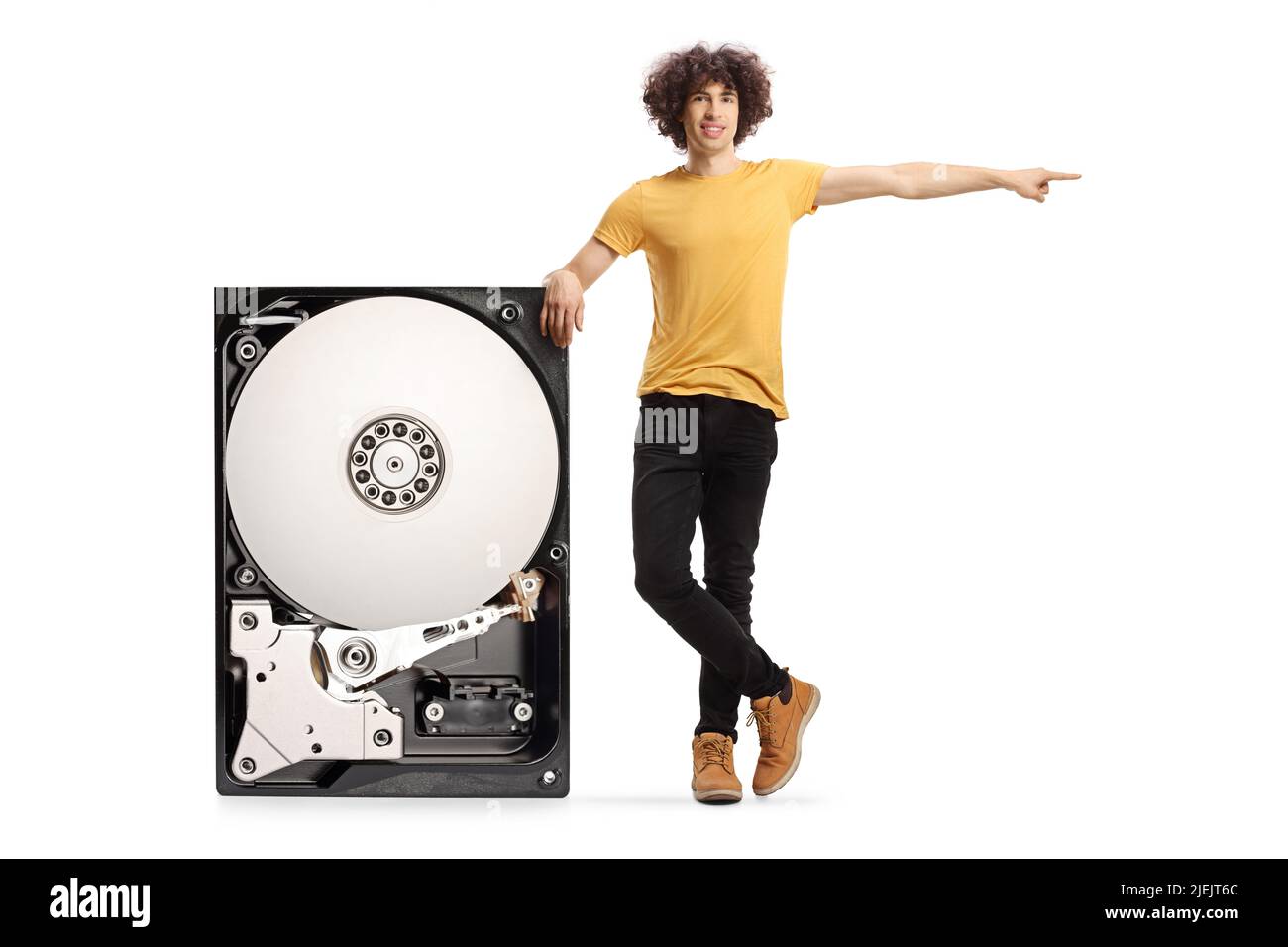 Casual guy leaning on a big computer hard disk and pointing to the side ...