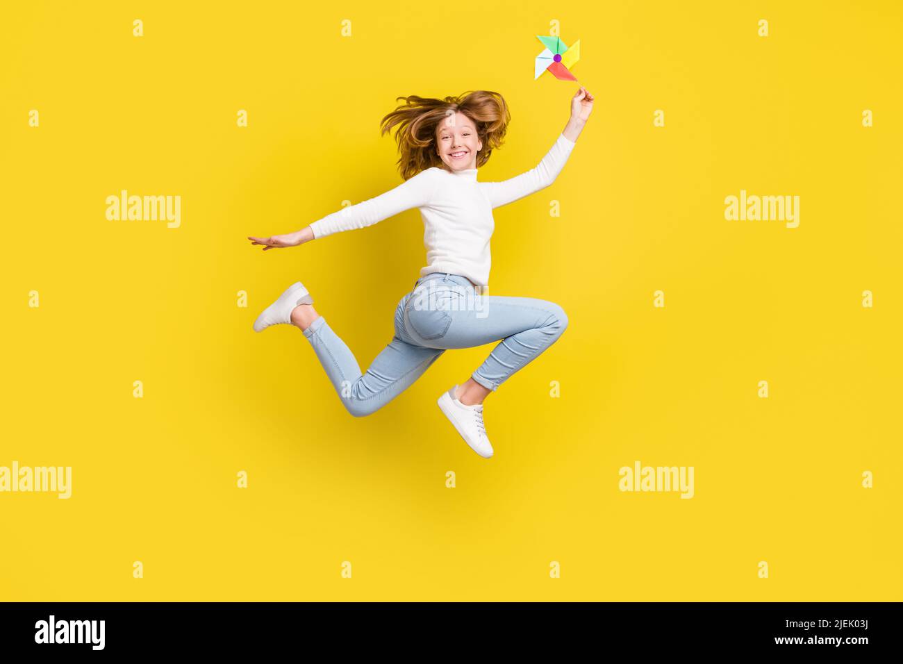 Full length photo of happy nice little girl jump up smile hold hand ...