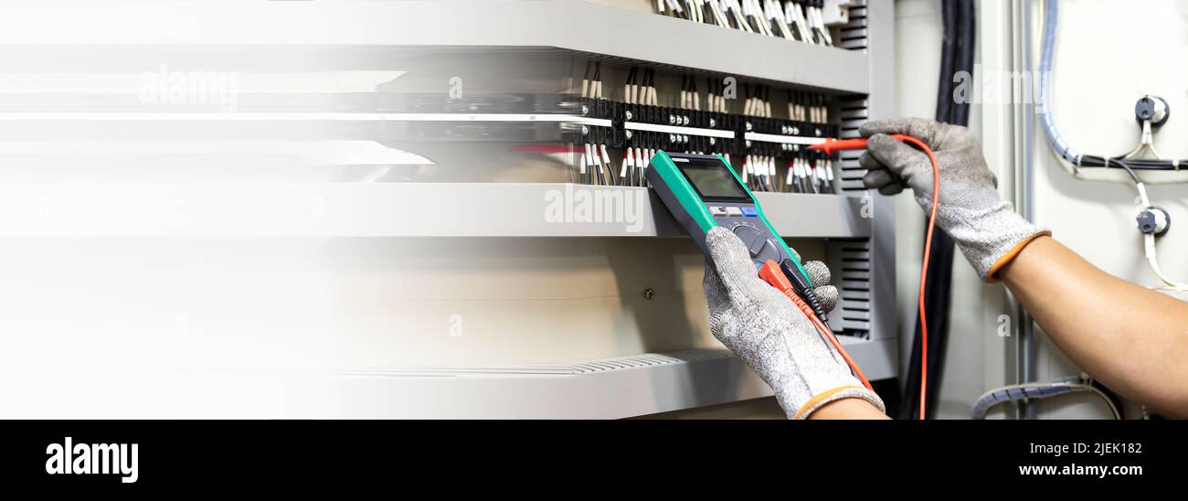 Electrical engineers check electrical control devices with a multimeter ...