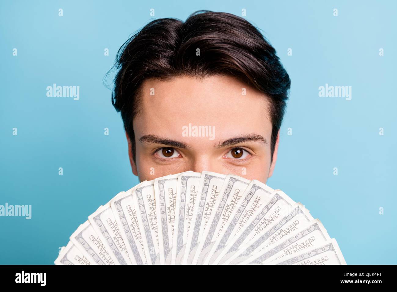 Photo of cute shy young guy dressed green hoodie holding money fan ...