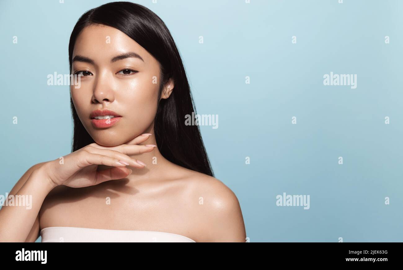Woman applying skincare product on her face. Asian woman putting ...
