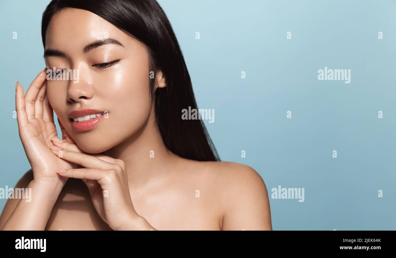 Hydrating and moisturizing. Young Asian woman applying face cream ...