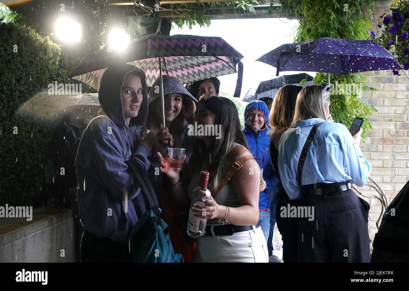 Spectators shield themselves from the rain during day one of the 2022 ...
