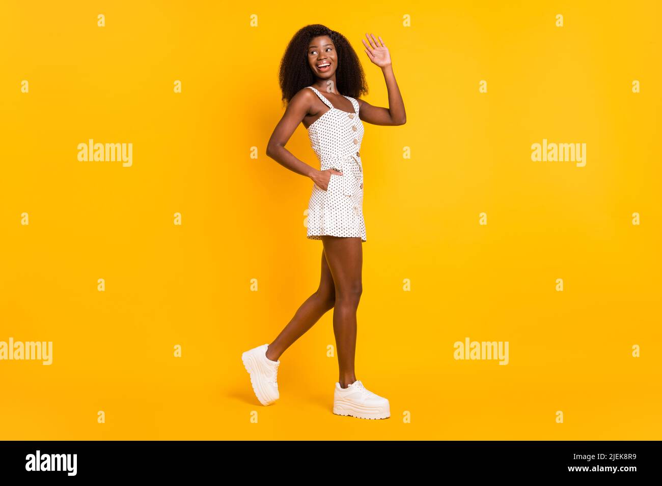 Full size photo of dark skin young lady go empty space wave hello ...