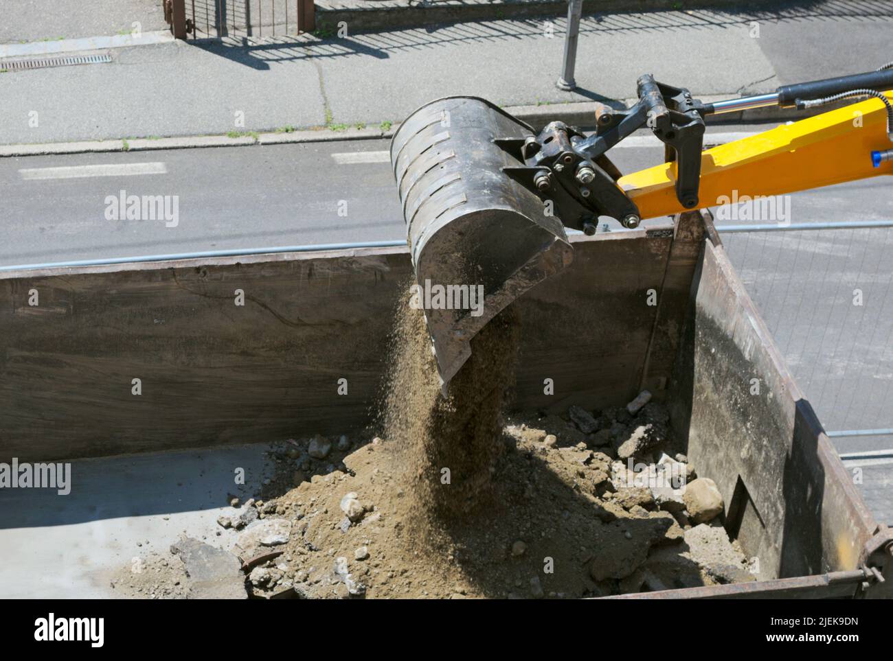 excavator loading soil for removal into dump truck during roadworks ...