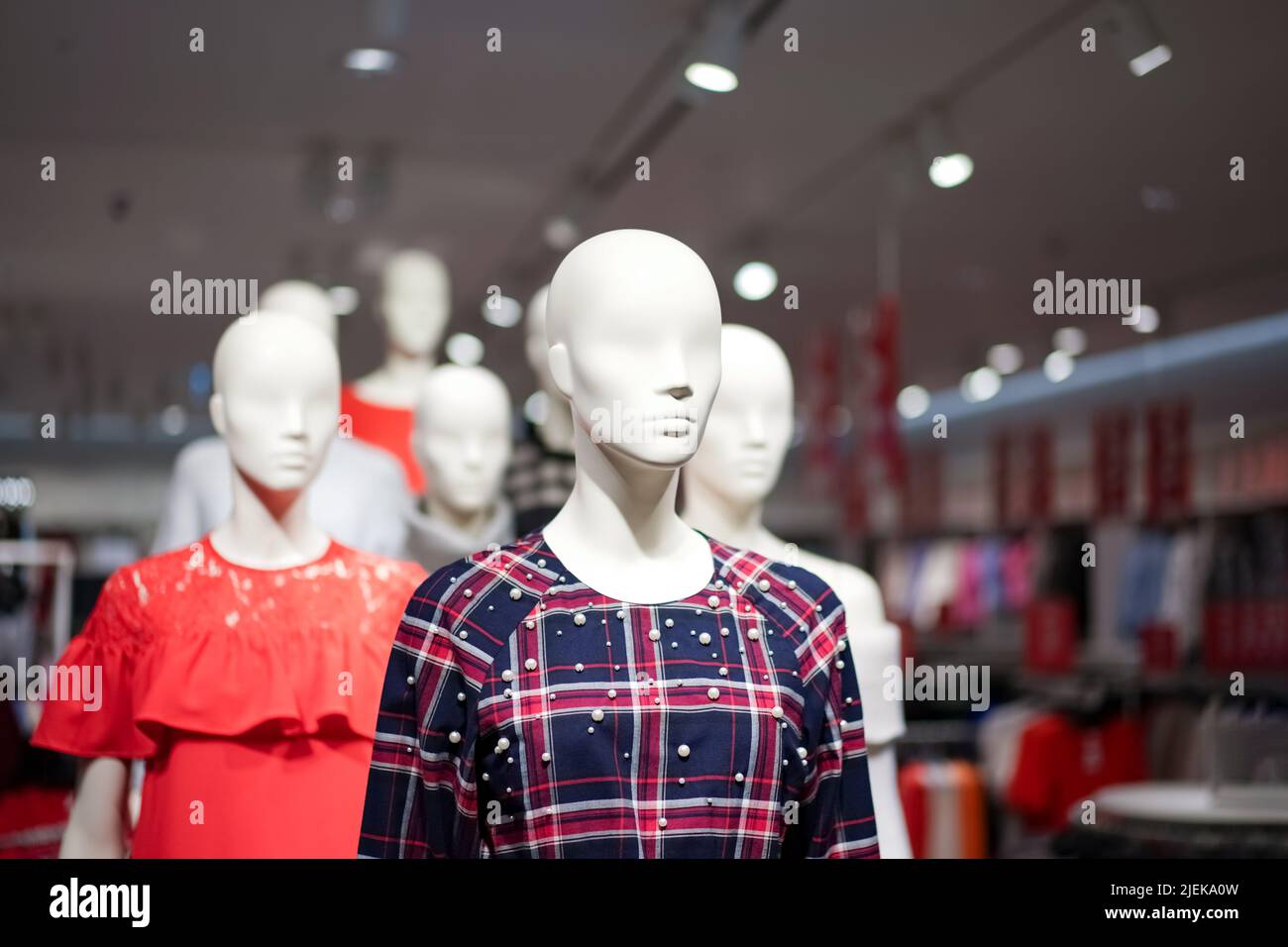 Female mannequins are dressed in casual clothes with a red-orange theme ...