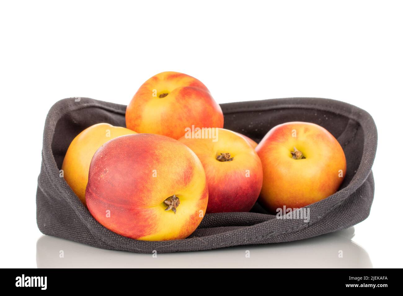 Several juicy organic nectarines in a linen basket, close-up, isolated ...