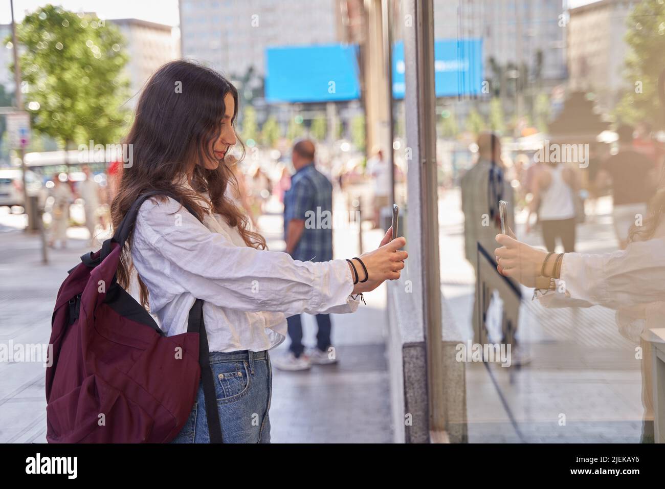 Woman looking in the window shopping, taking a picture of a display in ...