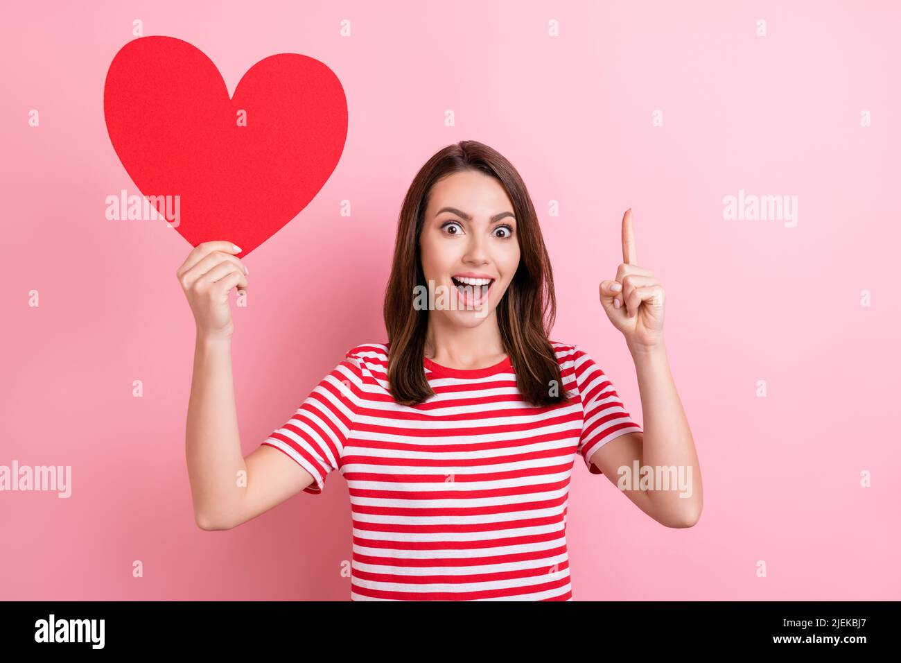 Photo of young woman happy positive smile hold paper heart point finger ...