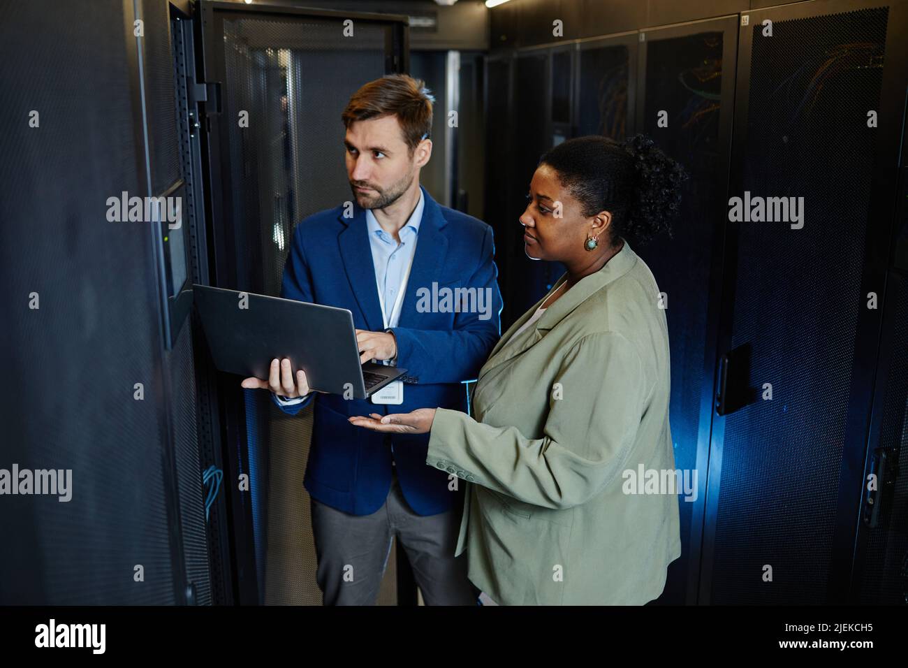 High angle view at two people in server room using laptop and checking ...