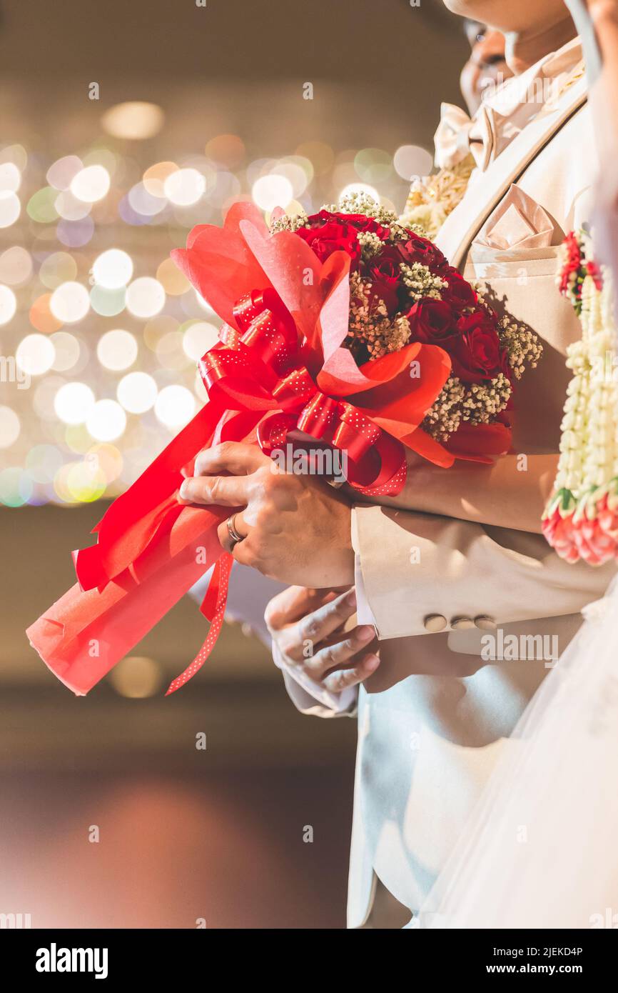 The hand of the bride and groom. Red roses bouquet at a party ...