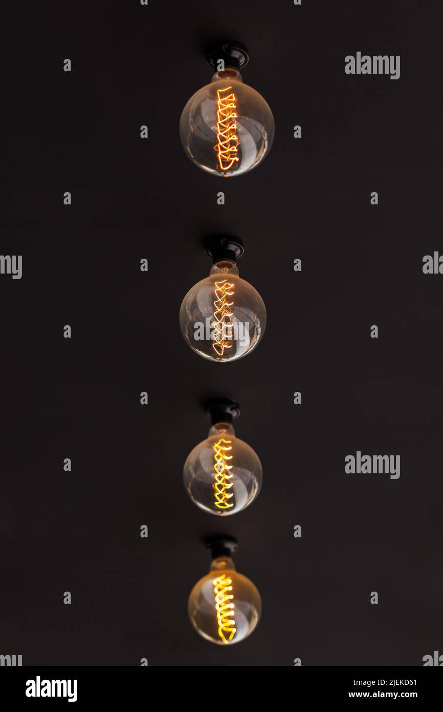 Old-fashioned light bulb turned on. On the dark surface, the concept of ...