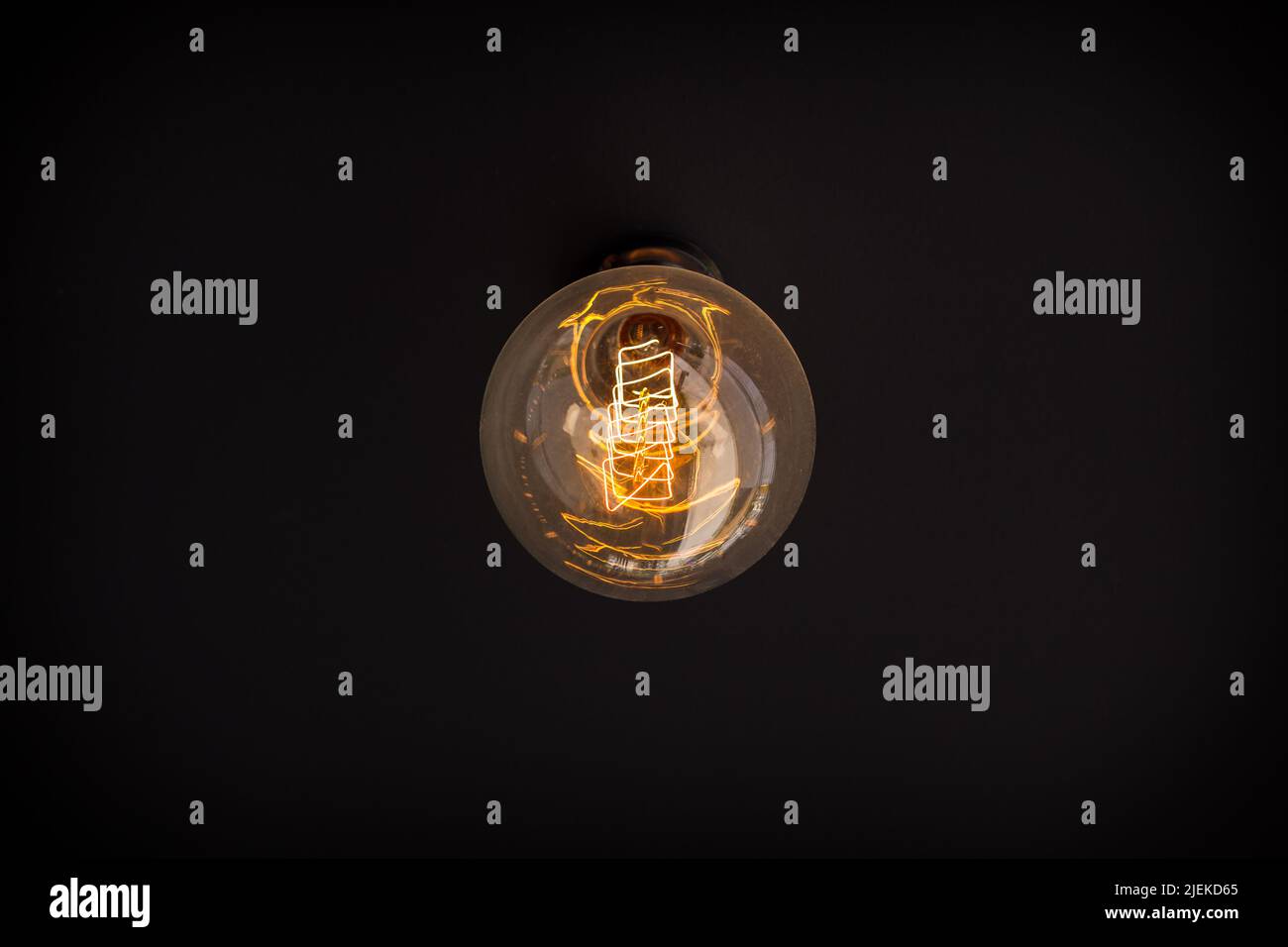 Old-fashioned light bulb turned on. On the dark surface, the concept of ...
