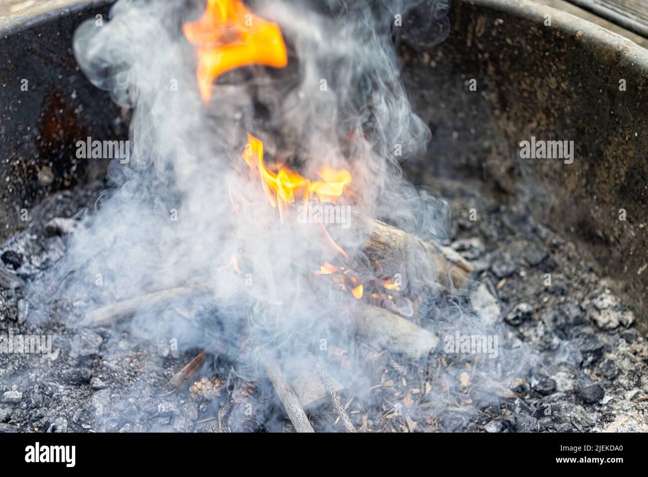 Closeup of smoke rising from logs wood branches and fire burning long ...