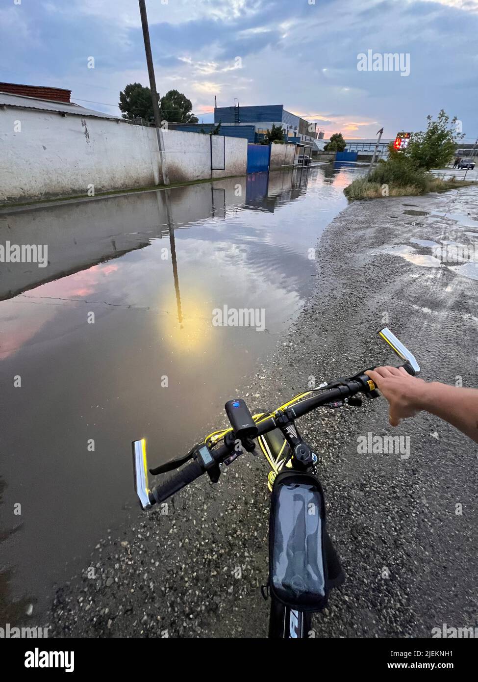 Man rides electric bike on wet road with puddle after rain against ...