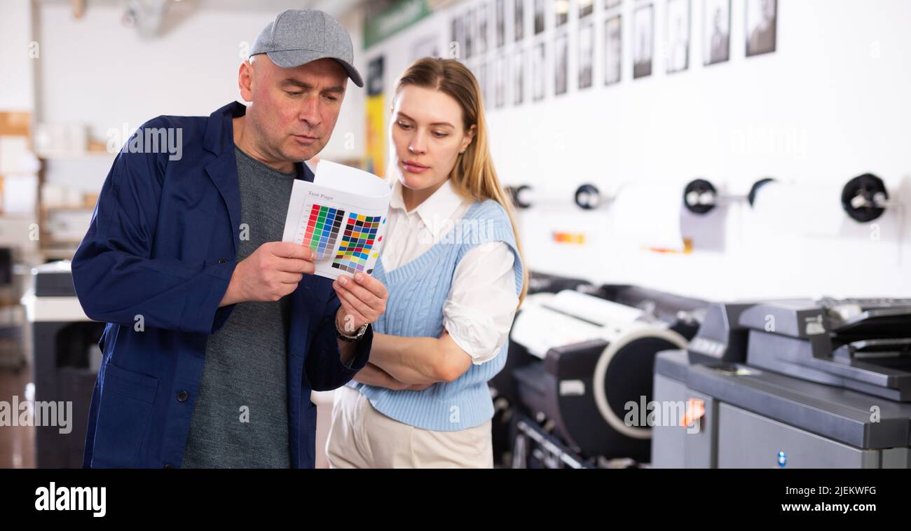 Service engineer and office worker checking color chart test page ...