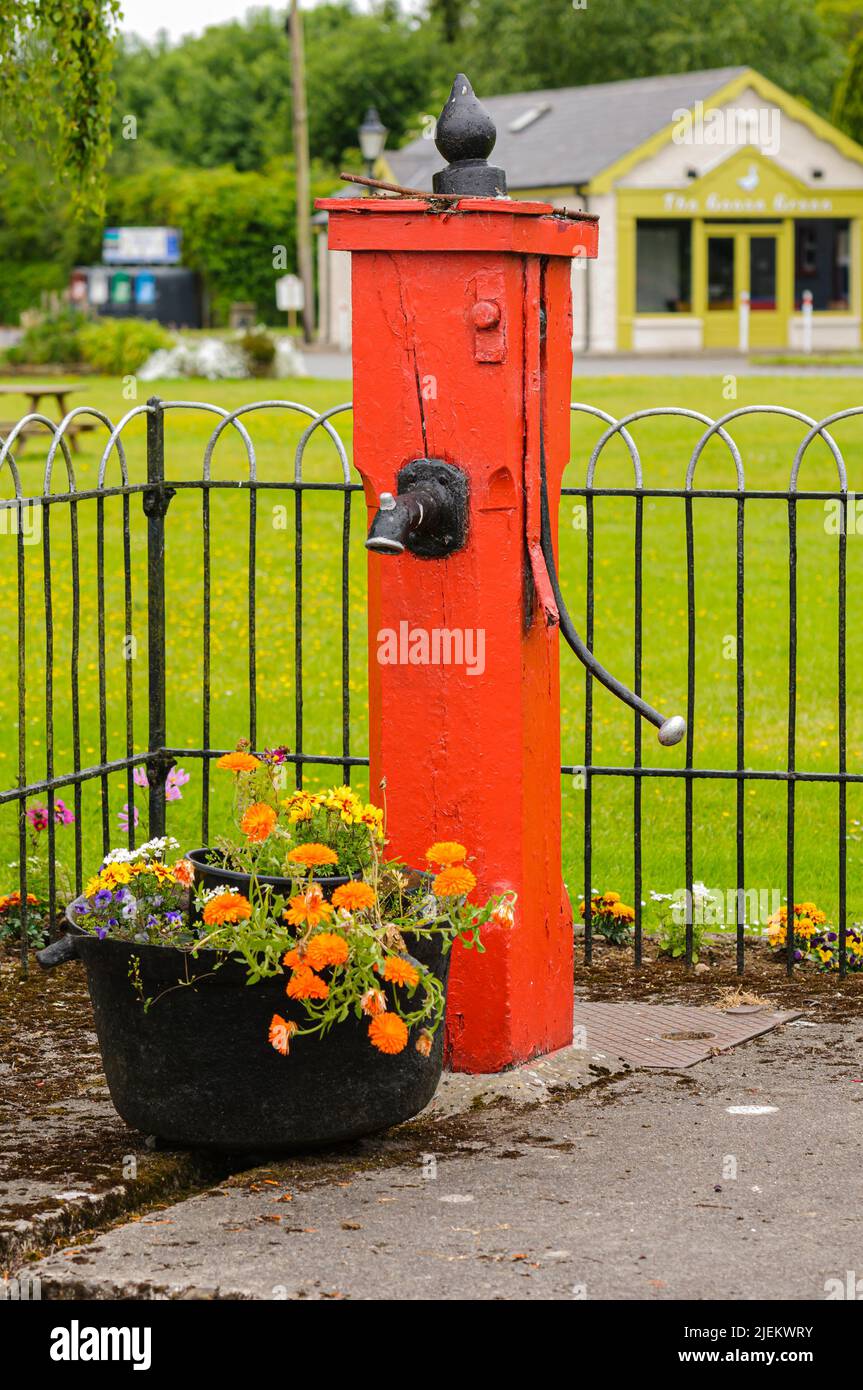 Traditional cow-tail water pump painted red on a village green Stock ...