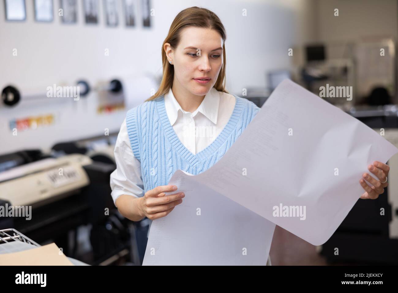 Worker checking paper in printing press workshop Stock Photo - Alamy
