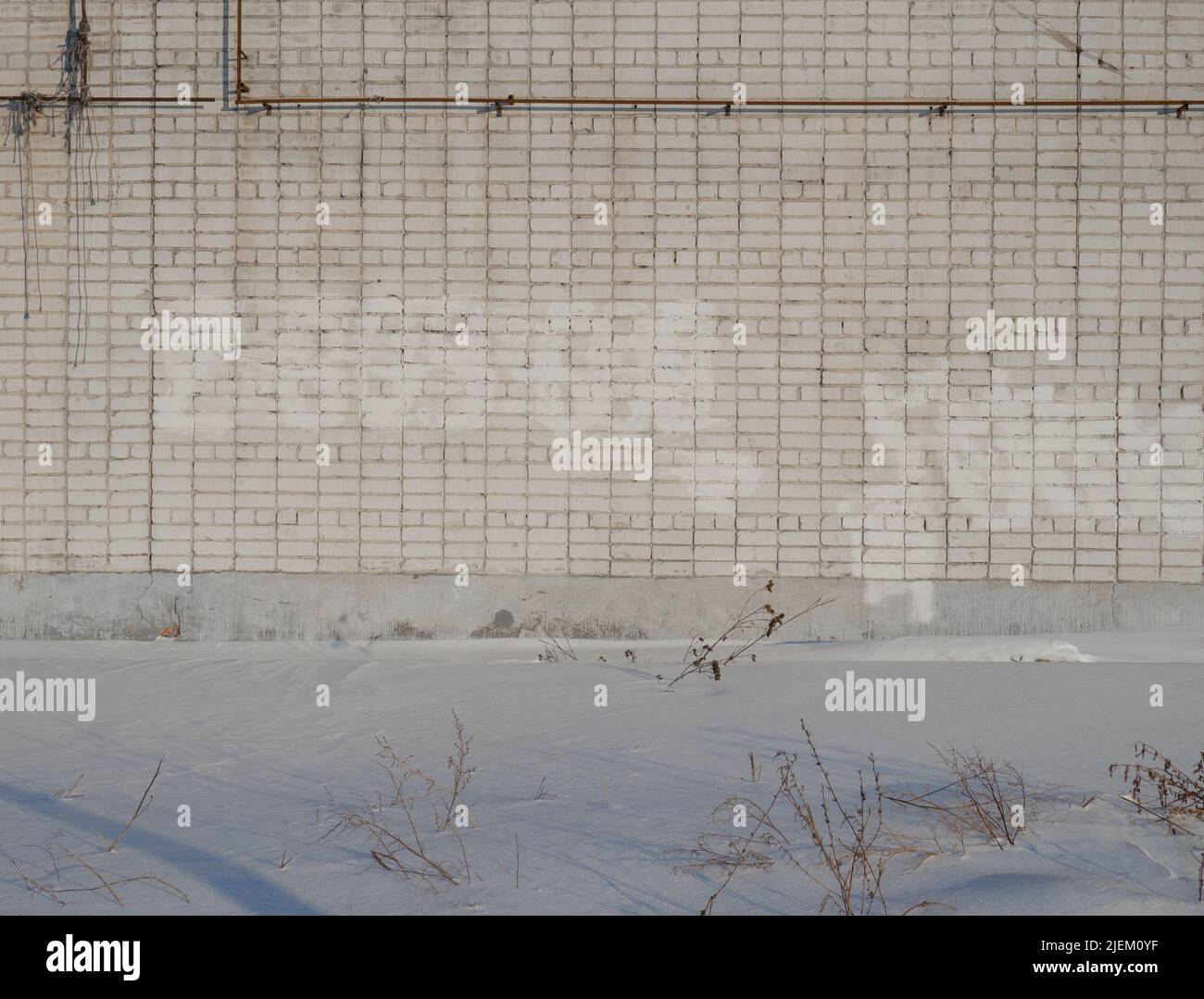 white brick wall and snow. Winter in the city. Unattractive cityscape ...