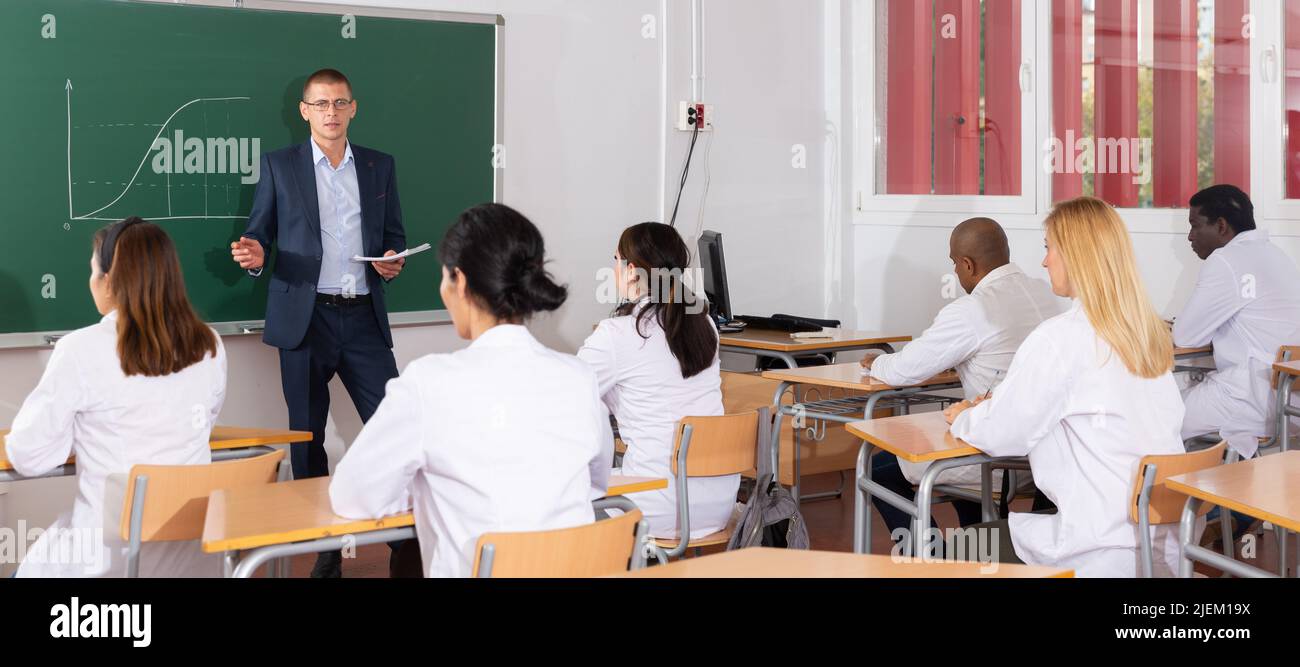 Teacher at chalkboard explains lesson to the students of medical ...