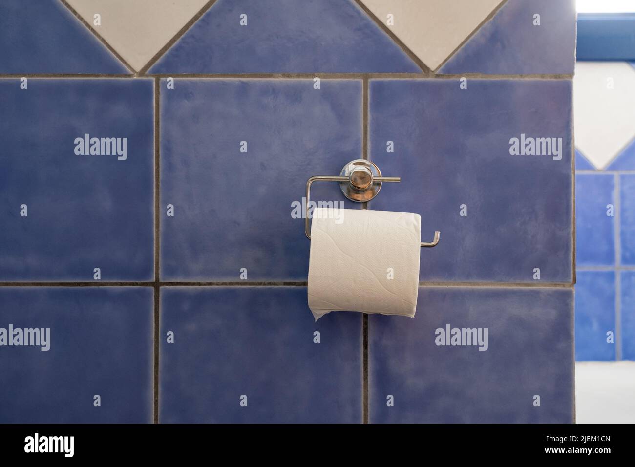 Roll of white toilet paper on metal paper holder. Toilet accessory for ...