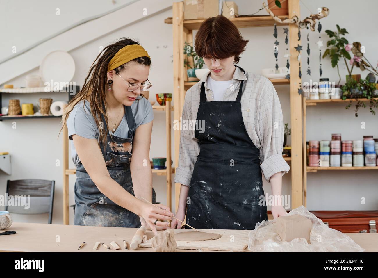 Young female master consulting her apprentice about creating ...