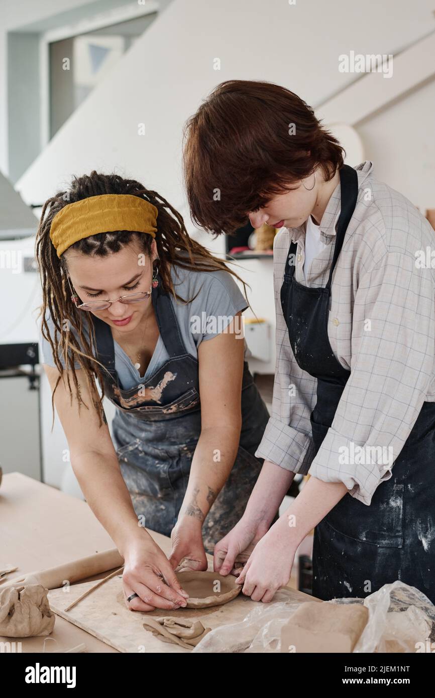 Young female tutor or master bending over table with flattened piece of ...