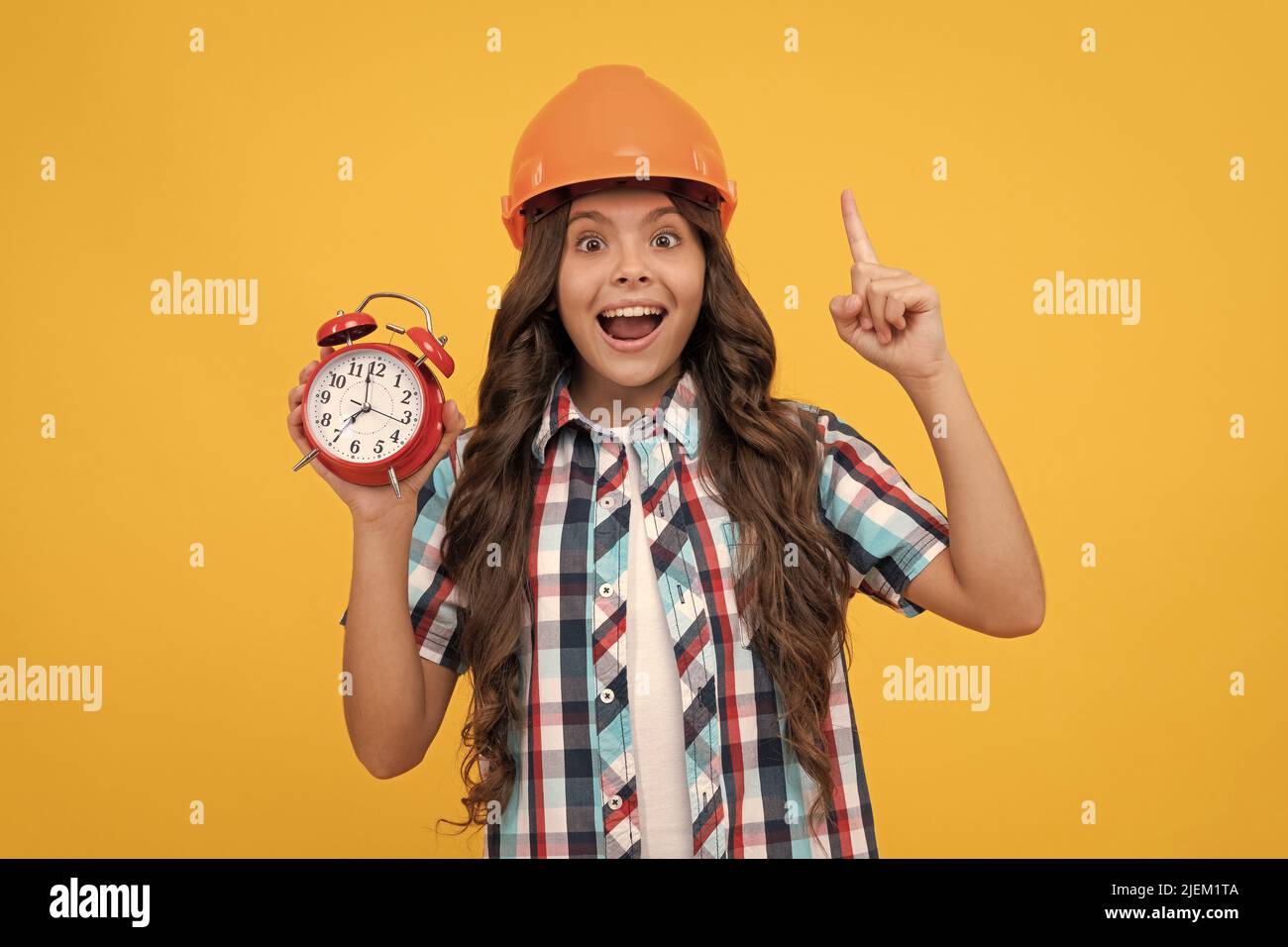 inspired kid with curly hair in construction helmet hold alarm clock ...