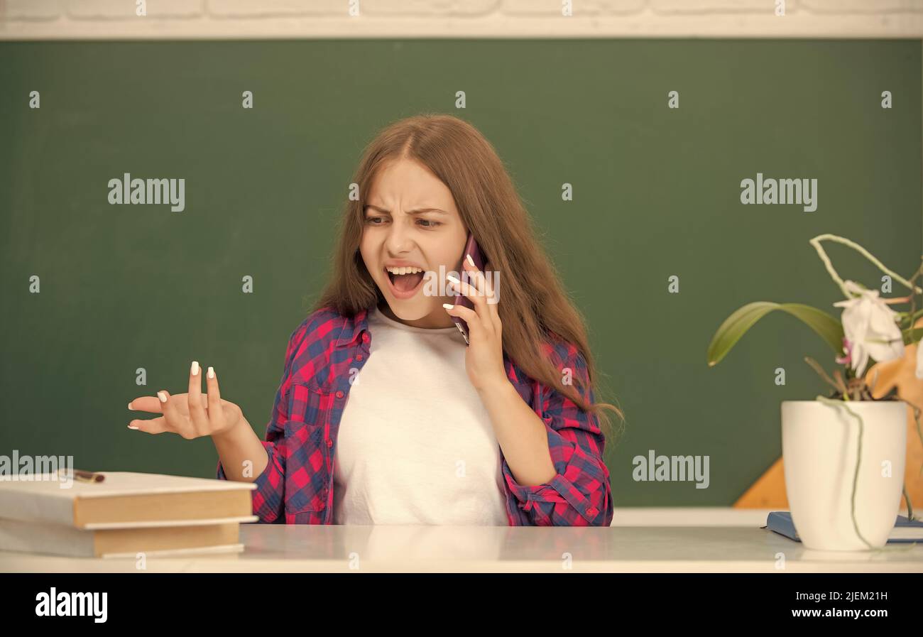 aggressive kid speaking on smartphone in classroom at blackboard, phone ...