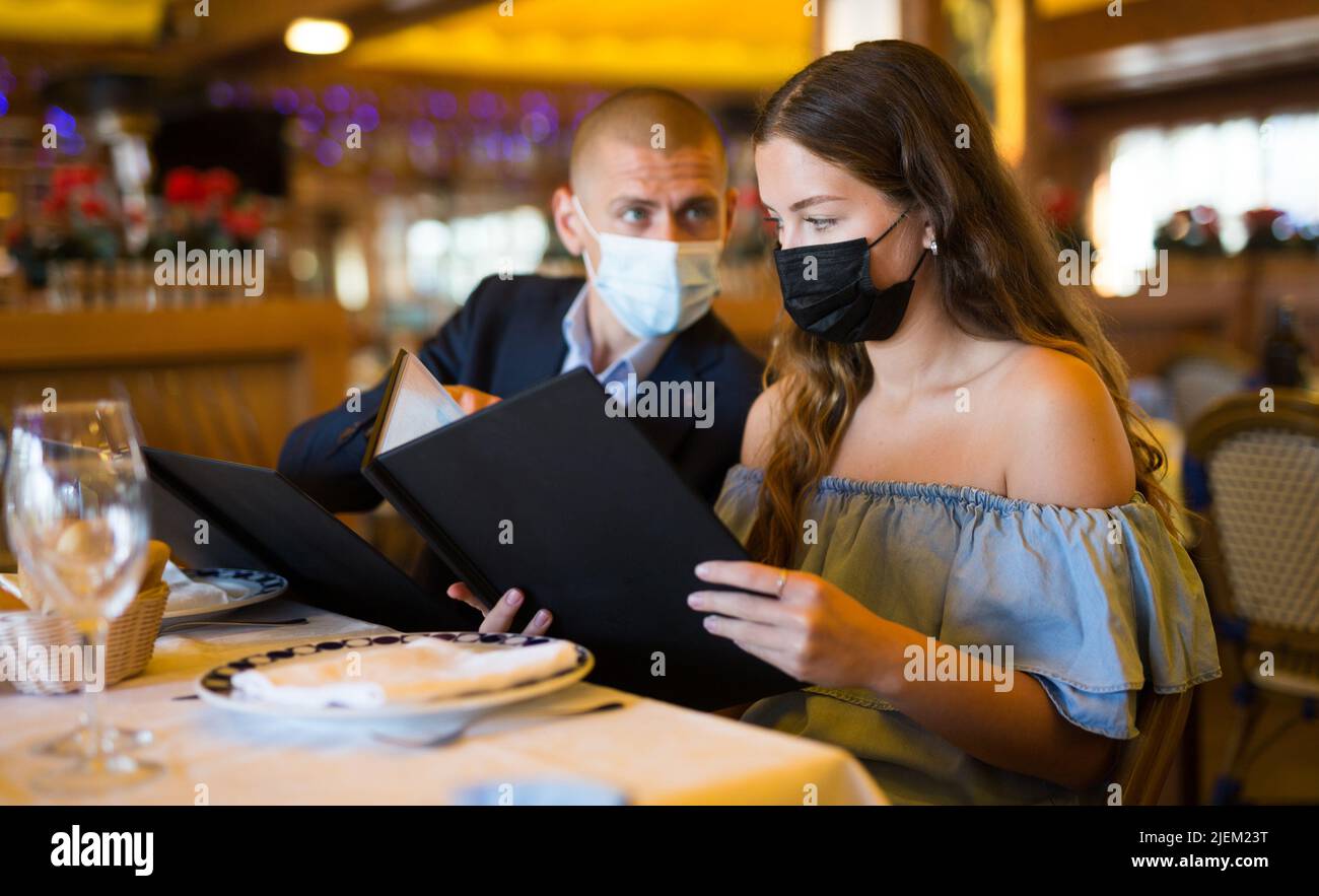 Couple choosing meals reading menu at restaurant Stock Photo - Alamy