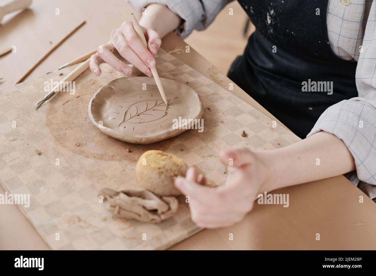 Hands of young female pottery master cutting leaf on clay plate ...