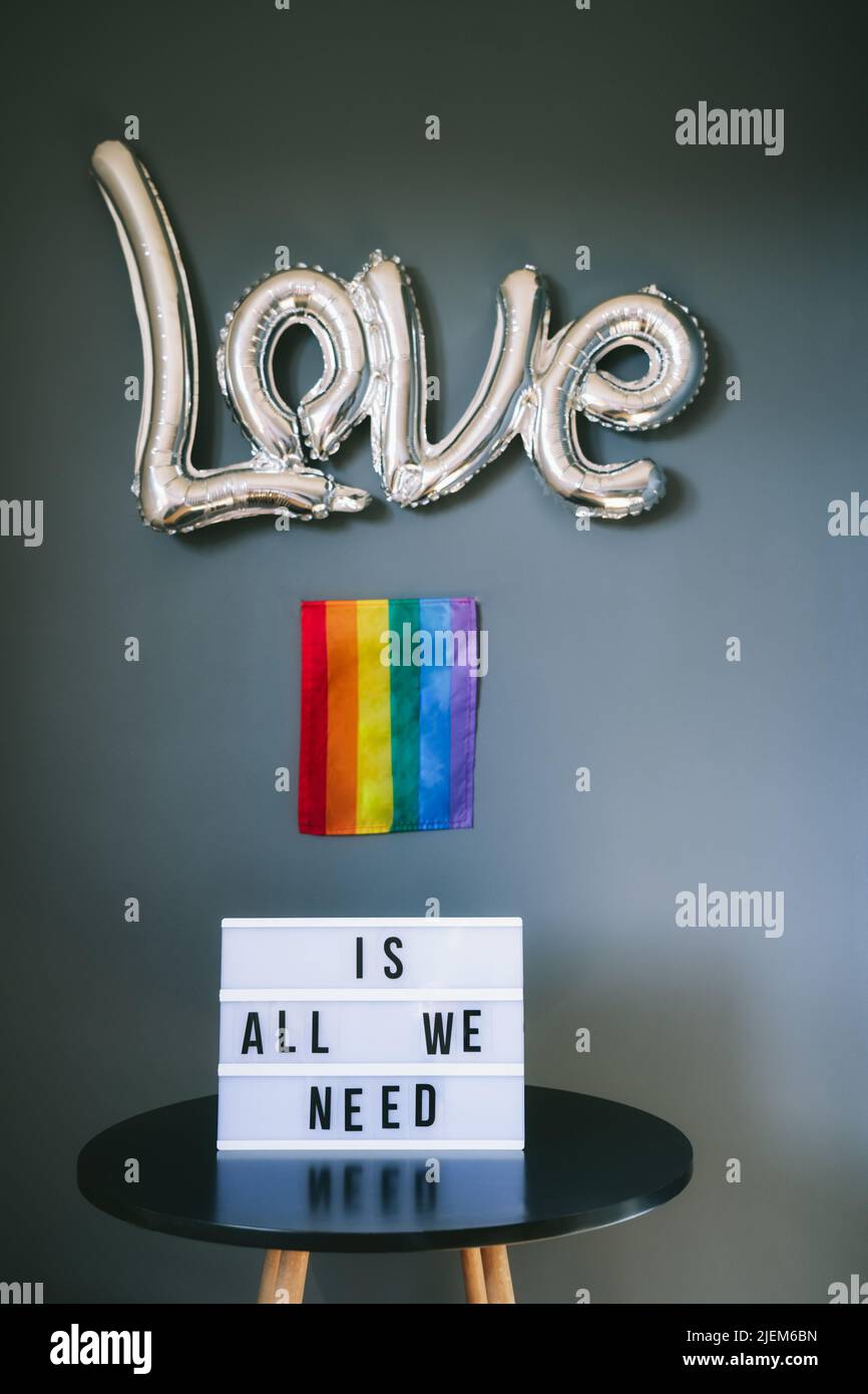 LGBTQ pride month background. A light box with the text Love is all we ...