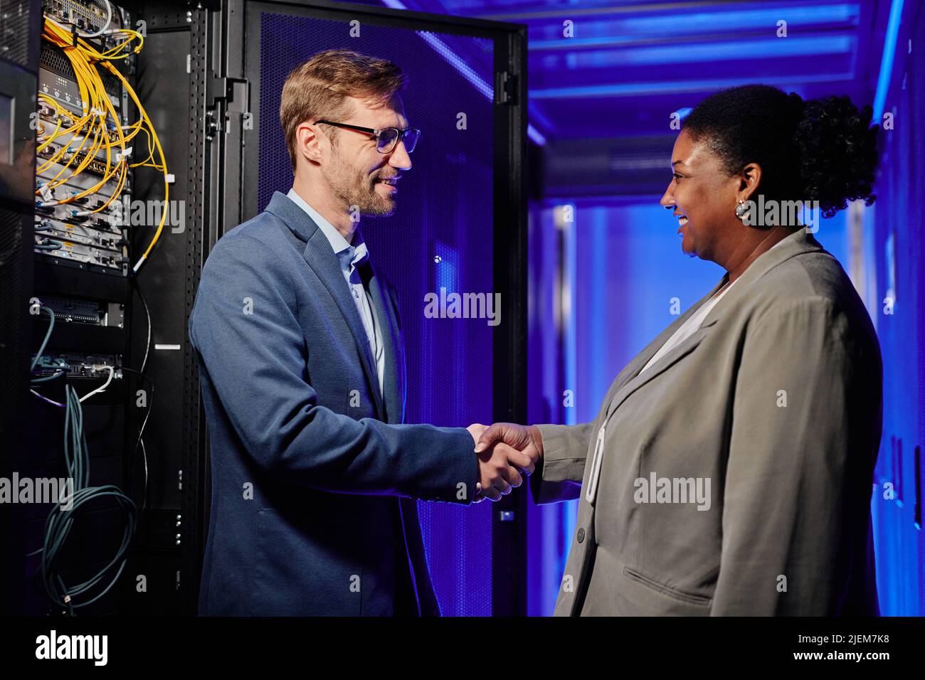 Side view portrait of two business partners shaking hands while ...