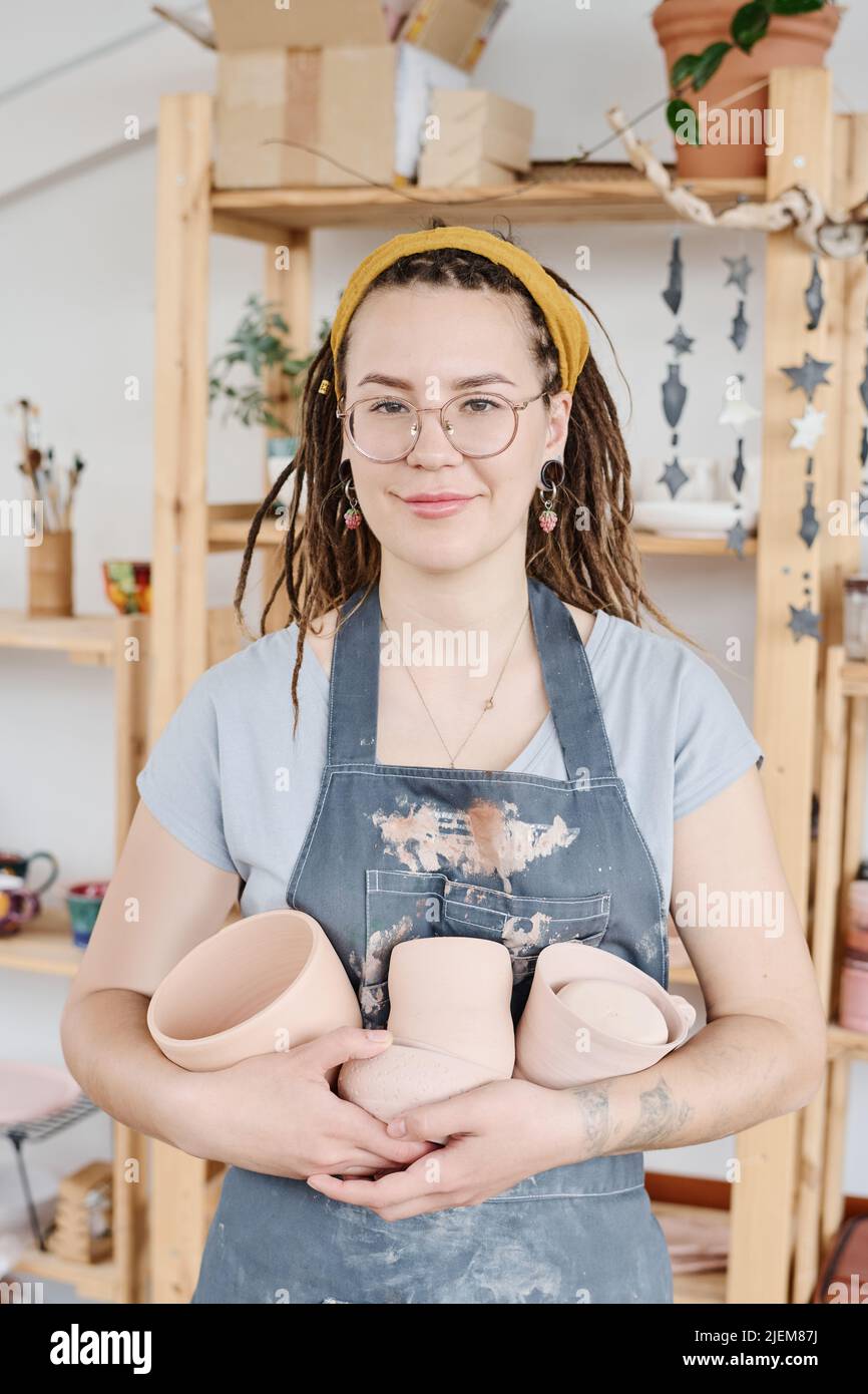 Young successful owner of earthenware shop holding handmade clay items ...