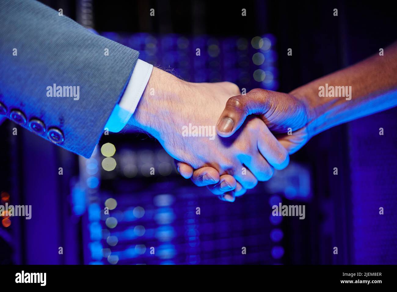 Close up of employer shaking hands with employee in server room ...