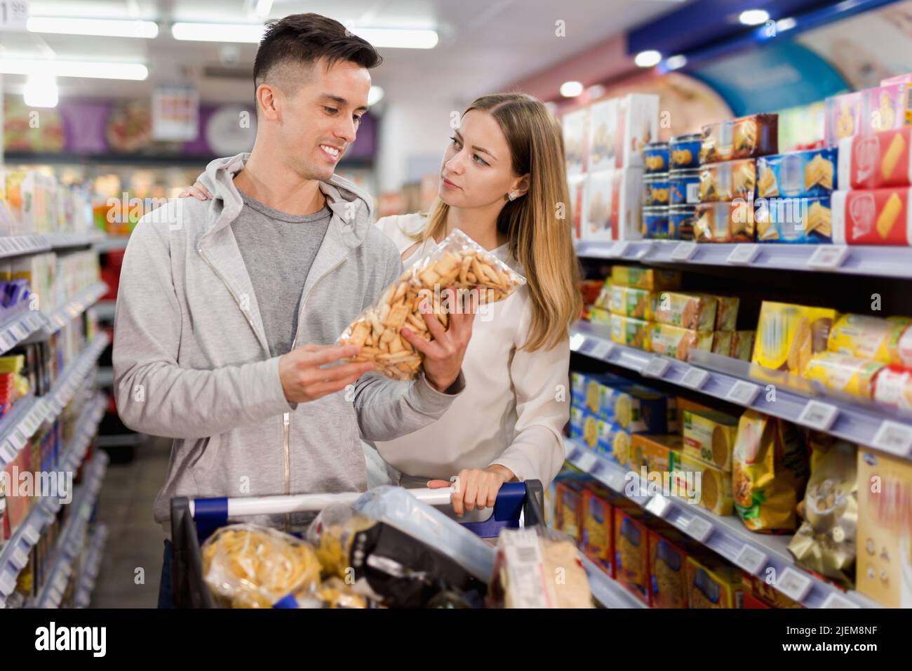 Young loving couple making purchases together, choosing cookies in ...