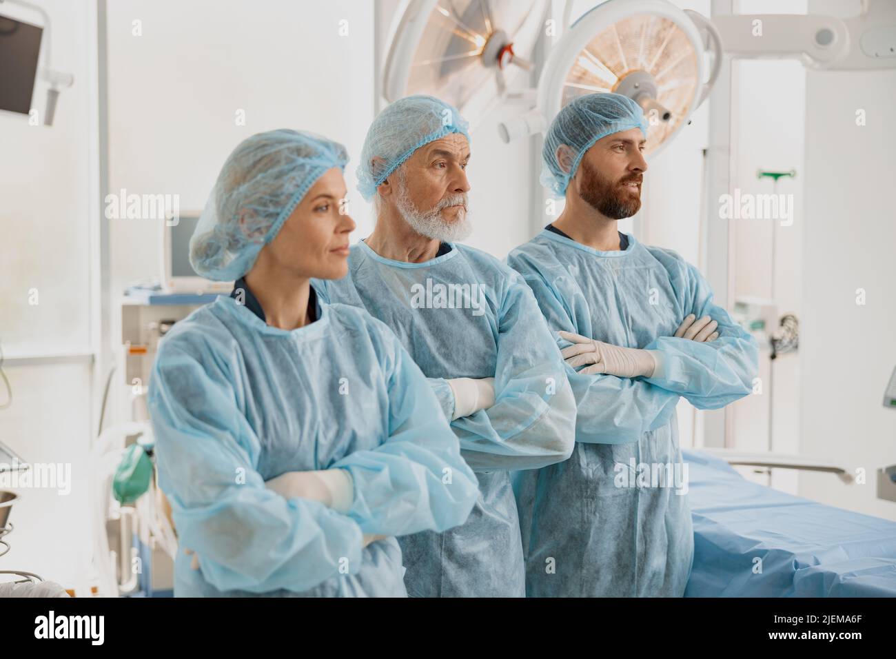 Team of professional surgeons with crossing hands standing in operating ...