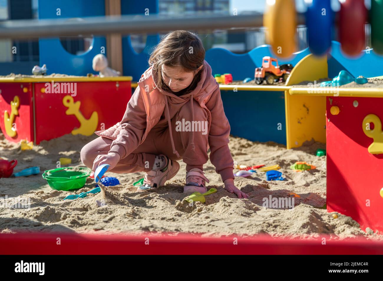 cute girl playing outside in the sandbox and making shapes out of a ...