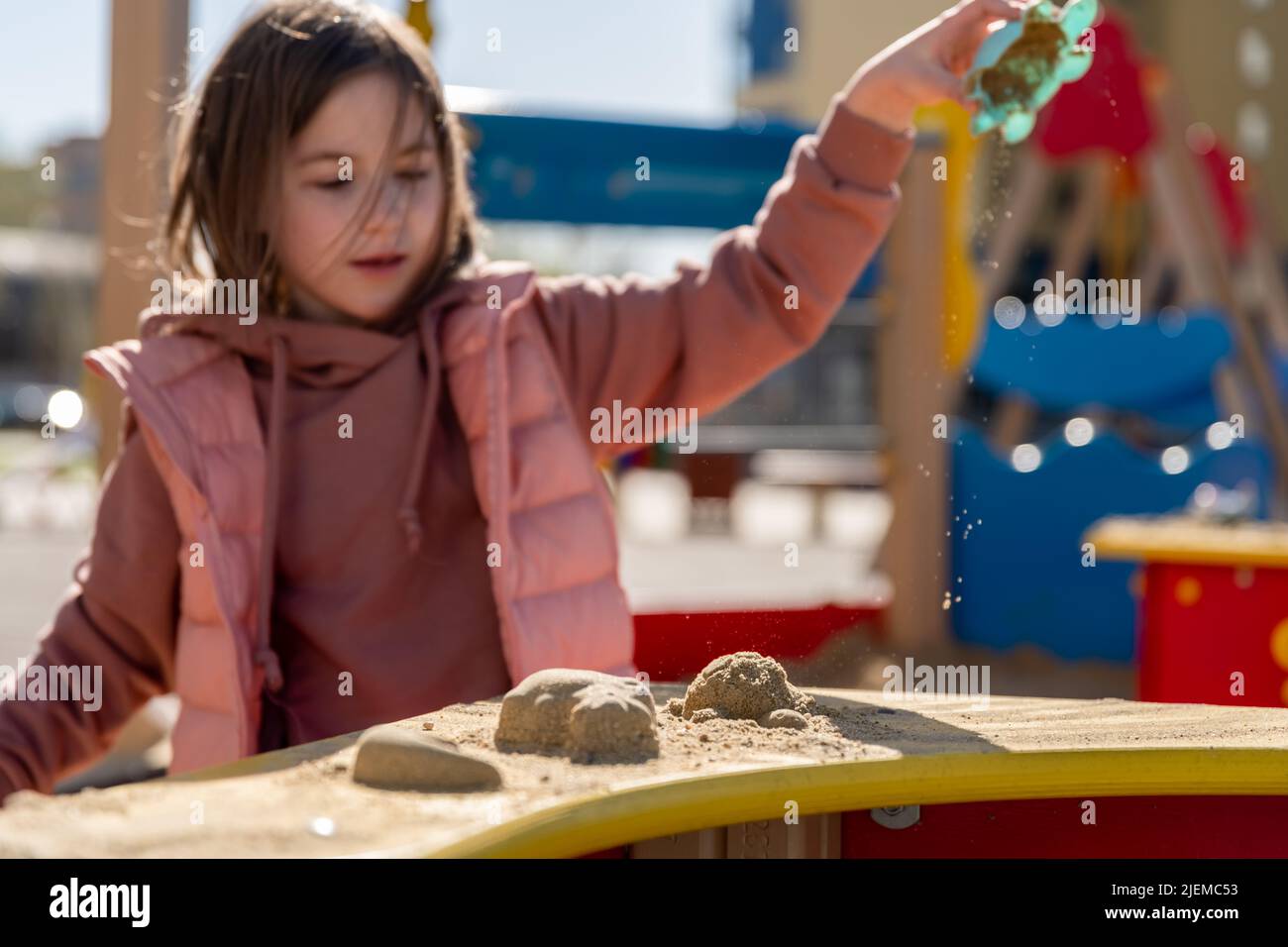 cute girl playing outside in the sandbox and making shapes out of a ...