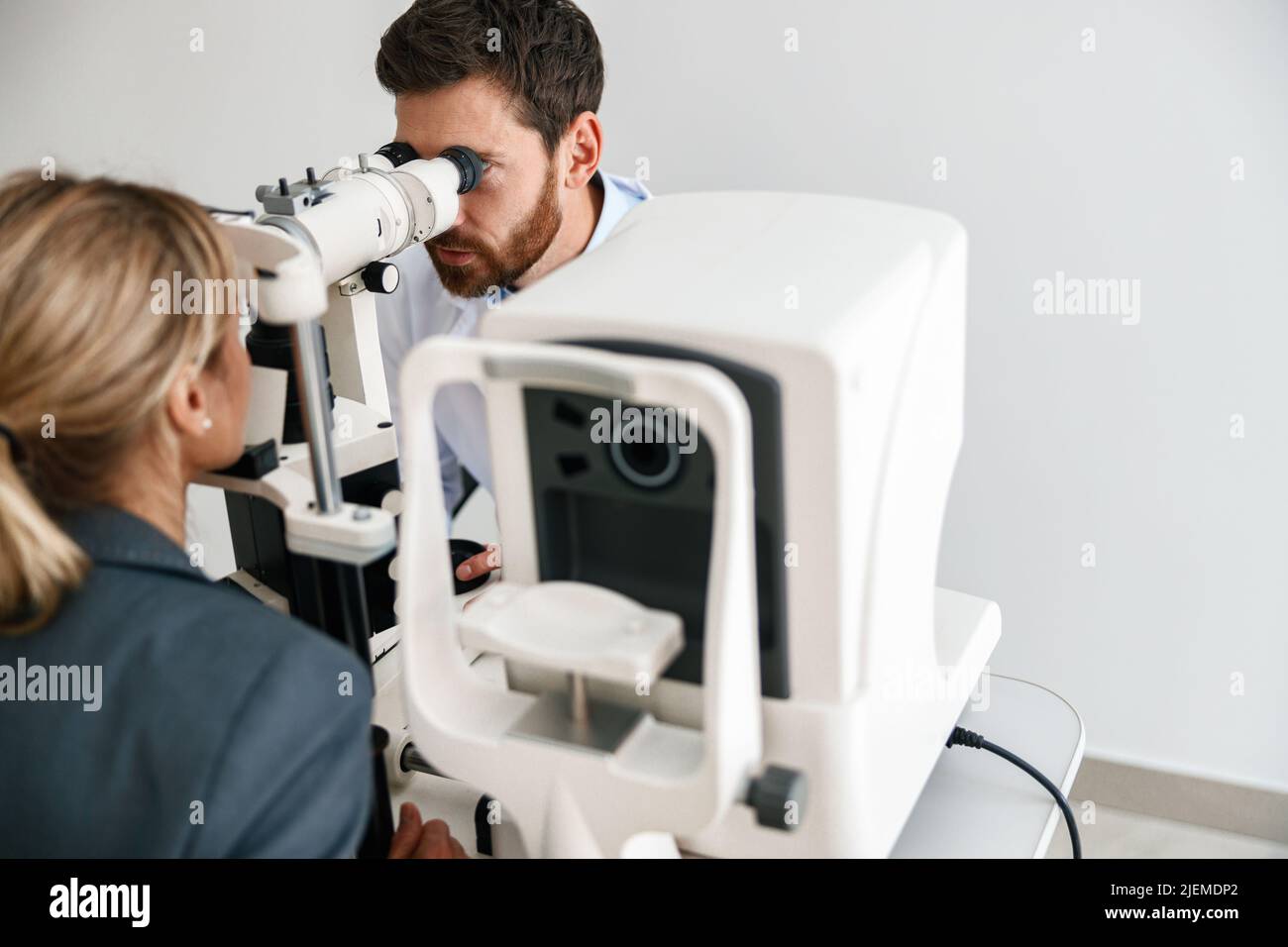 Ophthalmologist checks a patient's vision at an opticians shop or ...